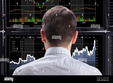 Side View Of A Young Male Stock Market Broker Analyzing Graphs On Multiple Computer Screens