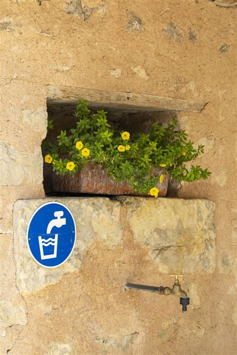 Drinking Water Source With Yellow Flowers And Sign In Le Poet Sigillat