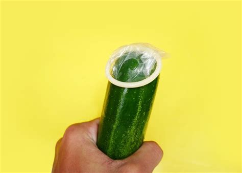 Premium Photo A Man Holds A Cucumber With A Condom On Yellow