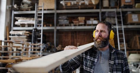 목수 작업장에서 실내에서 나무 판을 들고 청력 보호구를 가진 성숙한 남성 목수 중소 기업 개념입니다 사진 Unsplash의 목수 이미지