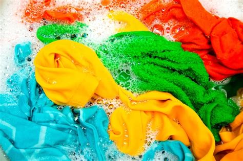 Premium Photo Colored Clothes Soaked In Water With Detergent And Foam