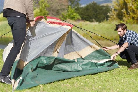 Teamwork Gets The Job Done Two Young Men Putting Up A Tent Outdoors
