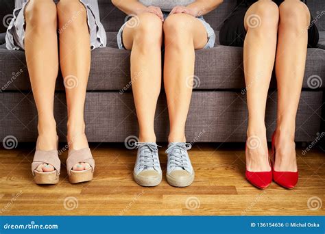 Three Girls With Legs Sitting On The Couch In Different Shoes And