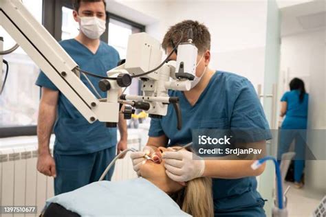 Male Endodontist With A Dental Microscope Repairing A Dental Cavity To