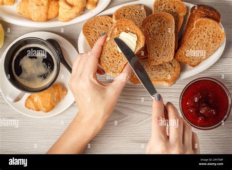 Female Hands Spreading Butter On A Toast With A Cup Of Black Coffee