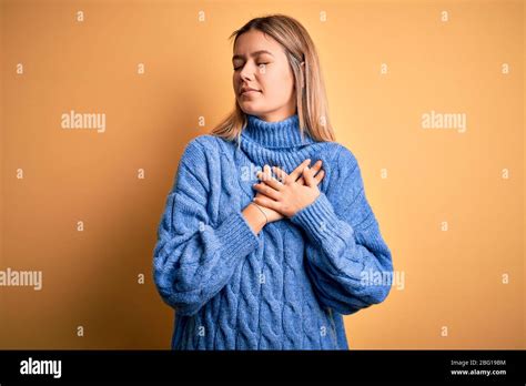 Young Beautiful Blonde Woman Wearing Turtleneck Sweater Over Yellow