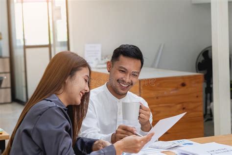 Two Male And Female Marketers Use Company Documents And Use Laptop Computers To Record Data To