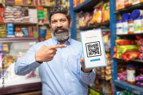 Portrait Of Happy Mature Indian Man Showing Qr Code Scanner To Pay