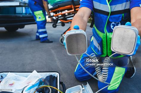 구급차 근처에서 사상자와 소생술을 구출하는 동안 제세동기 패드를 손에 들고 Ems 구급 대원 응급 의료 서비스 제세동기에 대한 스톡 사진 및 기타 이미지 Istock