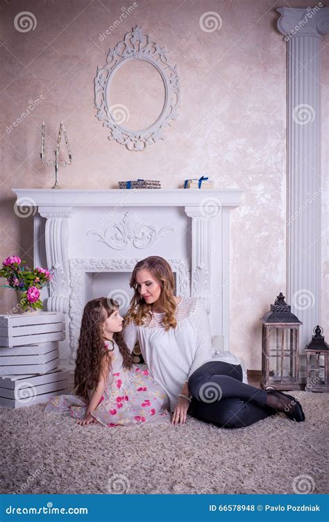 De Moeder En De Dochter Zitten Dichtbij De Open Haard Stock Foto