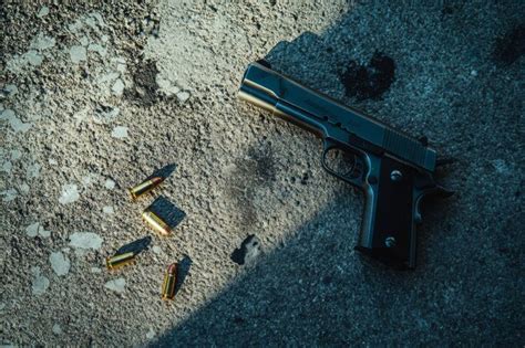 A Pistol And Shell Casings Lie On The Asphalt Evidence Of A Crime