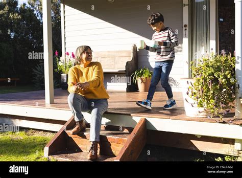 Happy Biracial Grandmother And Grandson Drinking Tea Sitting In Garden Stock Photo Alamy