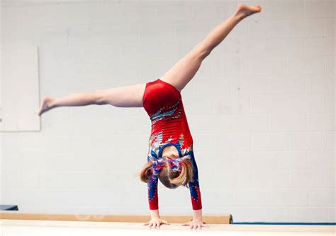 Download Young Gymnast Performs Cartwheel On Balance Beam Wallpaper