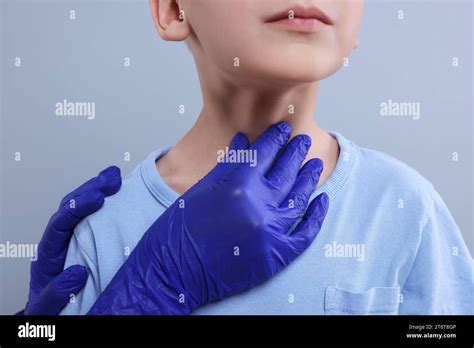 Endocrinologist Examining Boys Thyroid Gland On Light Grey Background