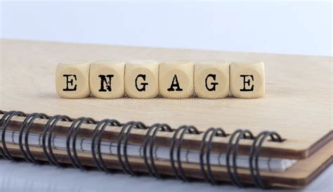 Word Engage Made With Letters On Wooden Blocks On Wooden Notepad Stock