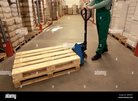 Worker Moving Wooden Pallets With Manual Forklift In Warehouse Closeup