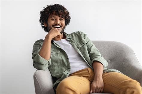 Chico Indio Alegre Sentado En Un Sillón En Casa Foto Premium