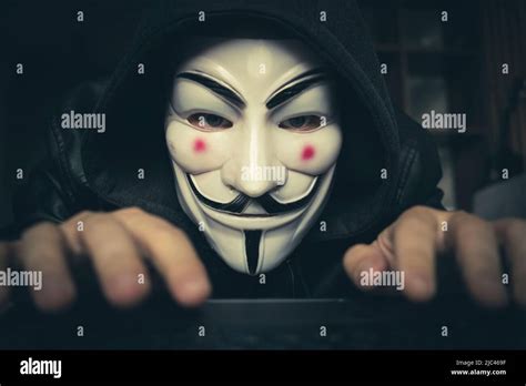 Hacker Cracker With Anonymous Association Mask Working On The Laptop Anonymous Is A Loosely