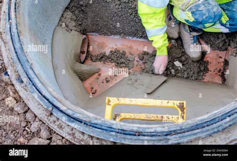 A Builder In The New Built Manhole Benching It With Sand And Cement Mix