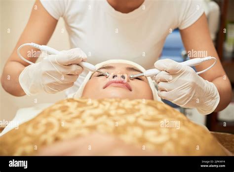 Highly Professional Beautician Using Microcurrent Machine While Carrying Out Procedure For Young