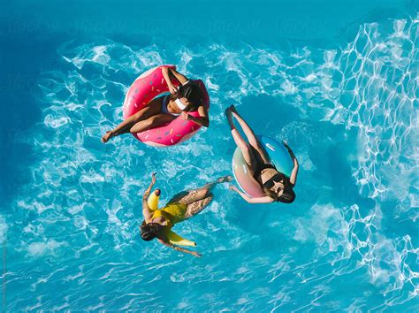 Women In The Water In A Swimming Pool On Top Of A Float By Stocksy