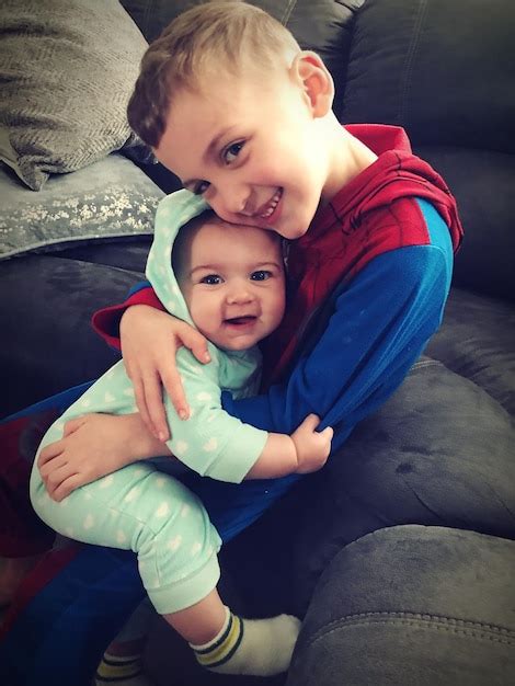 Retrato De Un Niño Lindo Abrazando A Su Hermana Sonriente Mientras Está
