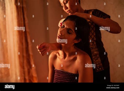 Asian Female Massagist In Traditional Clothes Giving A Thai Massage To