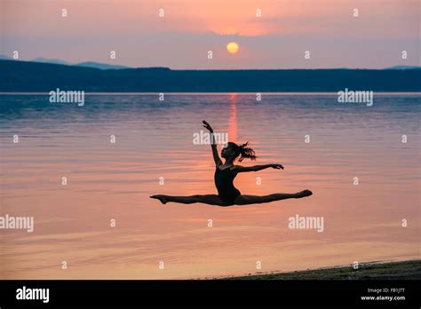 Seitenansicht des Mädchens Meer bei Sonnenuntergang springen in der