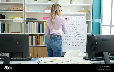 Young Blonde Woman Teacher Teaching Maths Lesson Writing On White Board