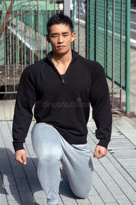 A Handsome Young Asian Male Clothed Muscular Bodybuilder Poses In A Park In Tokyo Stock Image