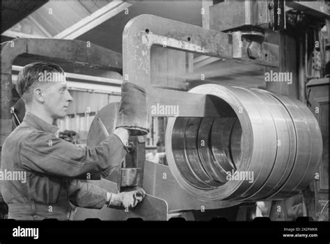 A British Factory Worker Removes Brass Coils From A Shearing Machine