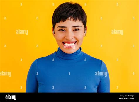 Happy Young Woman With Pixie Haircut Standing Against Yellow Background