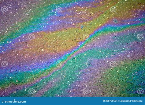 Colorful Gasoline Or Oil Spill Creating A Rainbow Sheen On Wet Asphalt