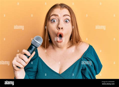Young Beautiful Redhead Woman Singing Song Using Microphone Scared And