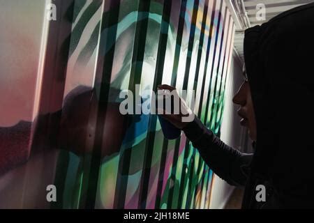 Side View Of African American Vandal In Mask Drawing Graffiti On Wall