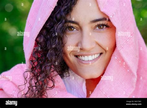 Smiling Arab Woman With Curly Hair Wearing Pink Hijab Standing In