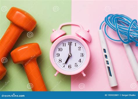 dumbbells alarm clock and skipping rope on a colored background the