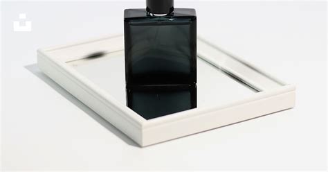 A Bottle Of Perfume Sitting On Top Of A Mirror Photo Free Cosmetic