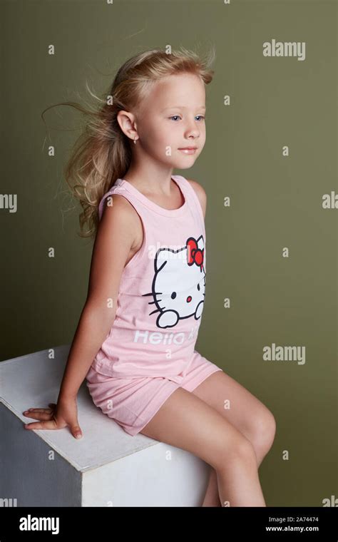 Brooding Beautiful Girl Sitting On A White Cube And Posing School
