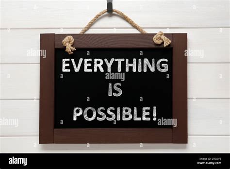 Small chalkboard with motivational quote Everything is possible hanging on white wooden wall ...