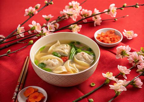 A Light Colored Bowl Of Dumpling Soup With Pink Flower Blossoms And