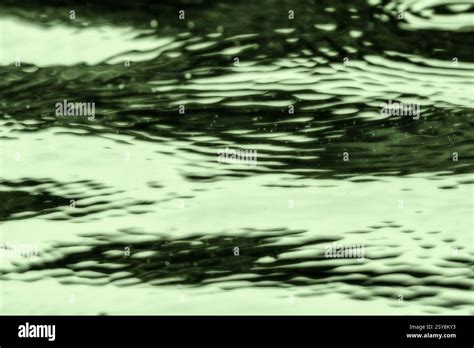 Abstract Close Up Of Green Rippling Water Surface With Reflected Light And Gentle Motion Pattern