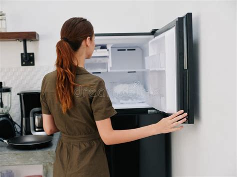 A Woman In The Kitchen Of Her Home Opened An Empty Freezer With Ice Inside Home Refrigerator