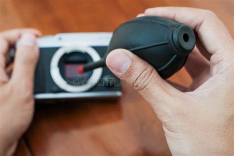 Cleaning The Camera Sensor With A Blower On Wooden Table And Cleaning