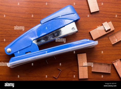 Blue Stapler And Piles Of Copper Office Staples On Wooden Office