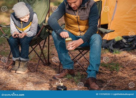 Cropped Shot Of Father And Son Eating Beans From Can Stock Image