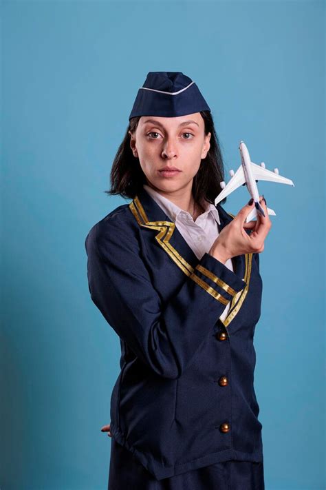 Premium Photo Flight Attendant In Aviation Uniform Holding Airplane