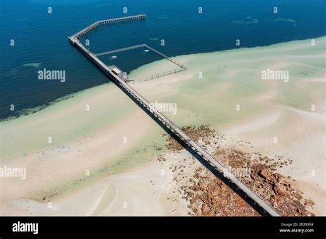 Aerial View Of A Long Narrow Jetty Stretching Out Into A Calm Coastal