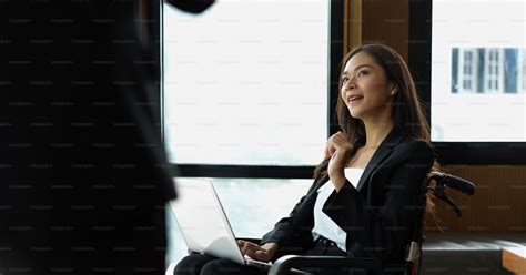 휠체어를 탄 매력적인 장애인 사업가가 매니저와 이야기를 나누고 만나는 동안 노트북으로 작업하고 있다 사진 Unsplash의 태국 이미지