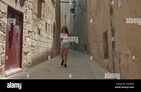 Beautiful Woman In Sunglasses Walking Alone In An Alley Through Old